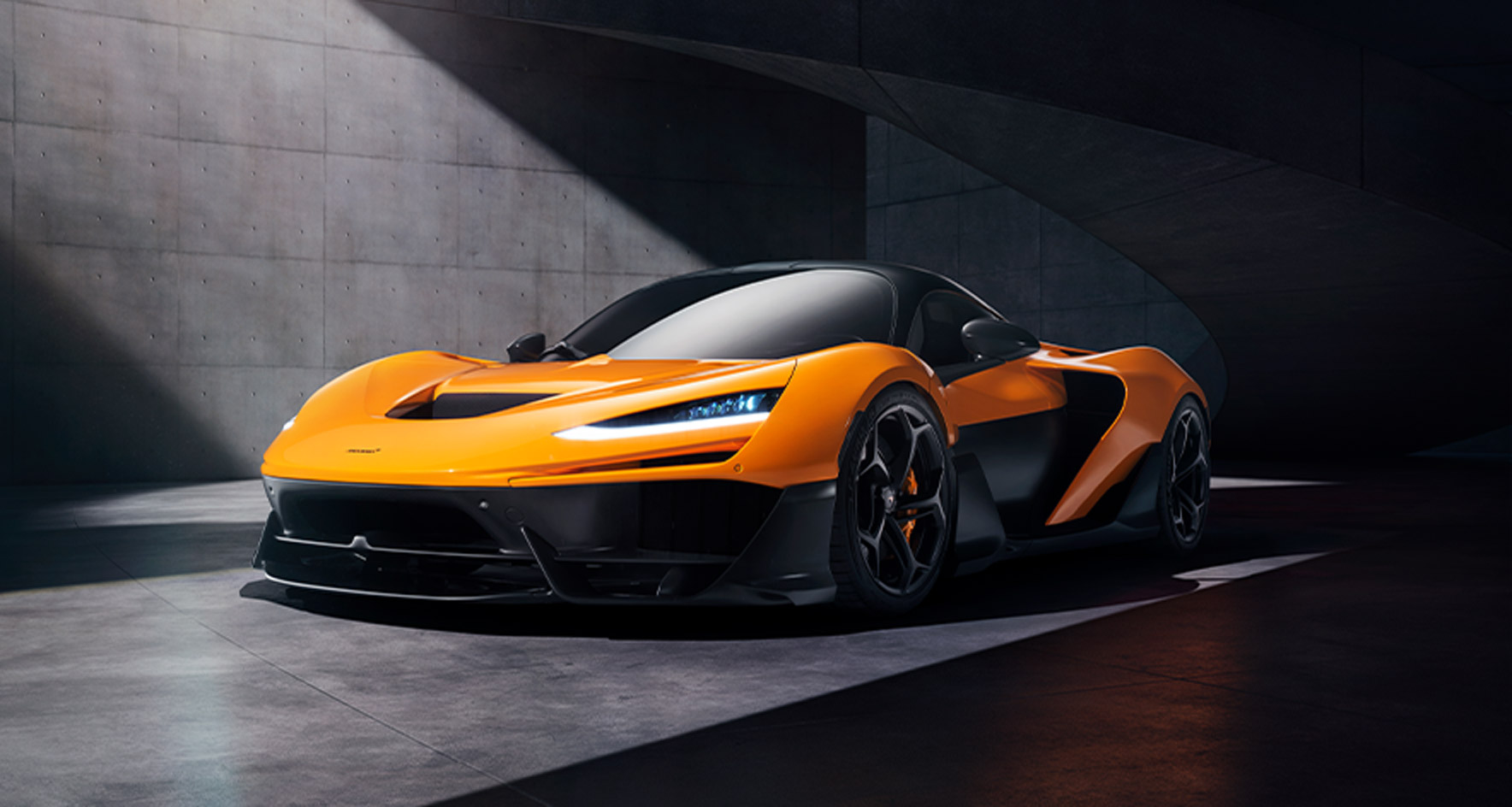 A bright orange McLaren Artura sports car is parked in a dramatic ...